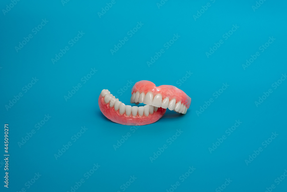 Full removable plastic denture of the jaws. Set of dentures on a blue ...
