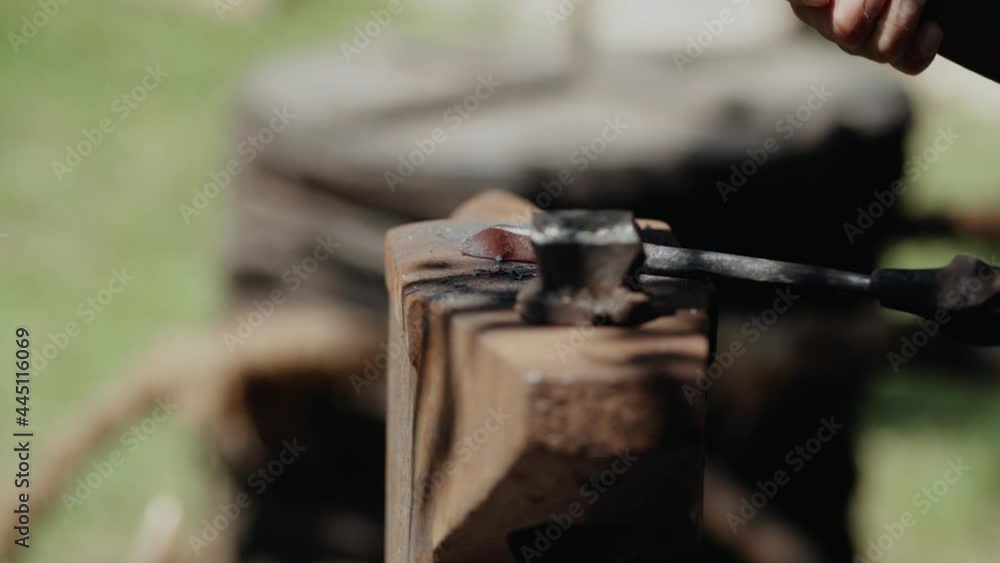 Ancient craft of blacksmithing. The blacksmith holds red-hot iron with ...