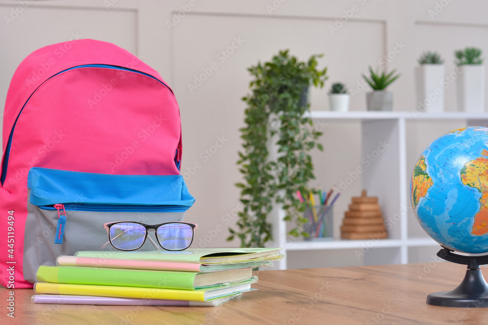 Backpack, school supplies on the background of the school classroom ...