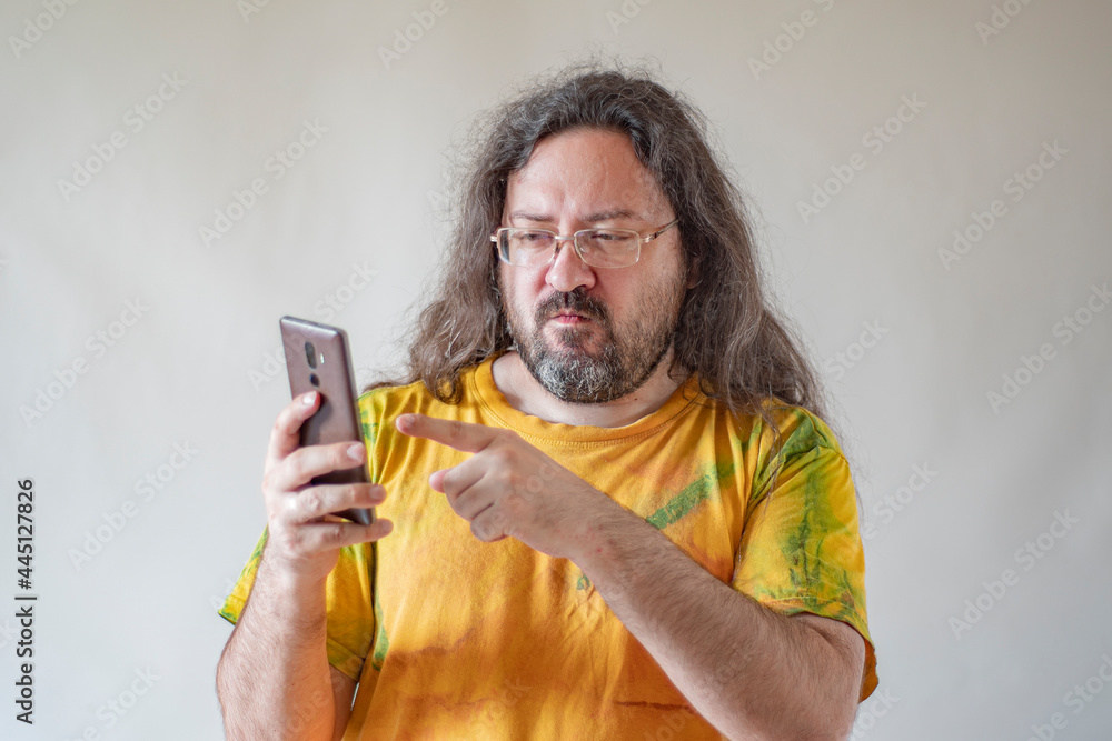 The man looks angrily at the phone. A casually and sloppy dressed man ...