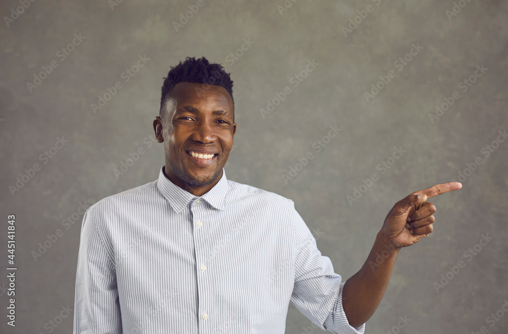 Happy handsome young black man smiling and pointing away with his first ...