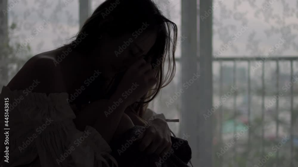 Depressed Asian woman sitting alone on the bed in the dark with cuddle ...