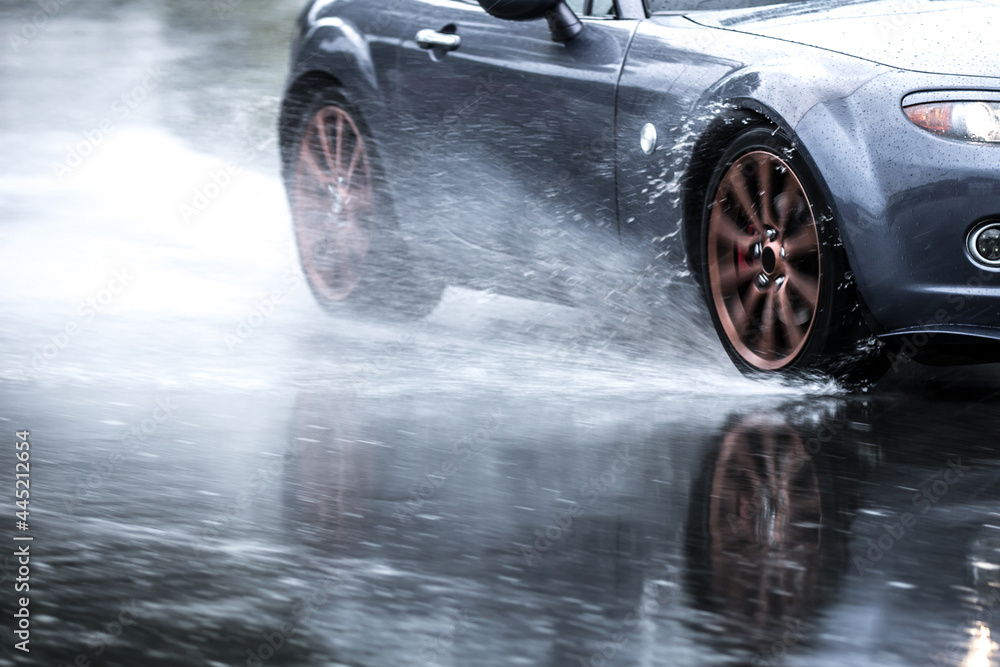 Sports car driven on rainy roads close up on a wheel with motion blur ...