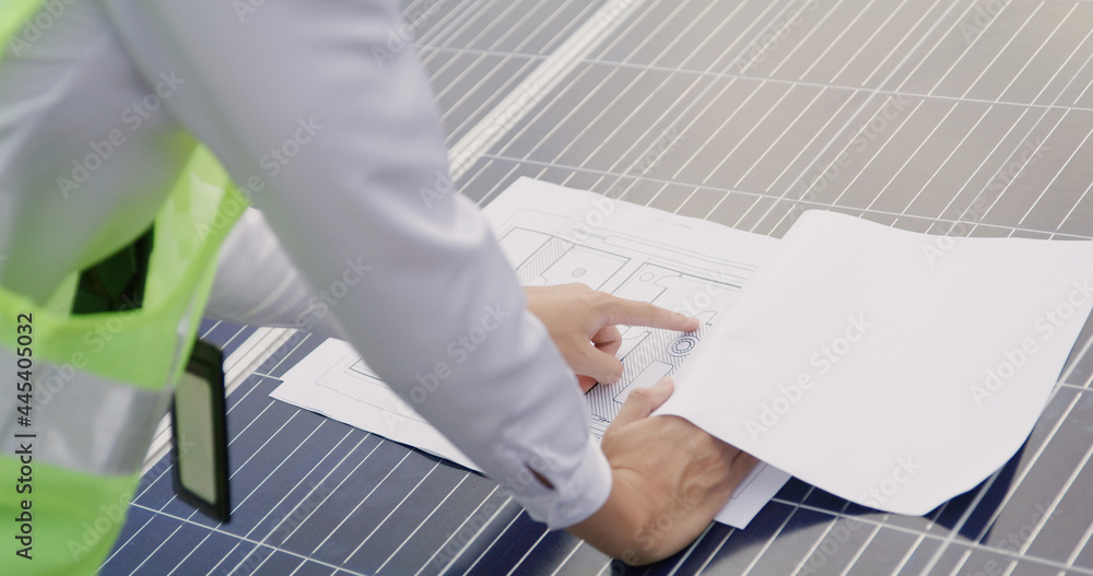 Engineer open blueprint of solar farm project on solar cells panel ...