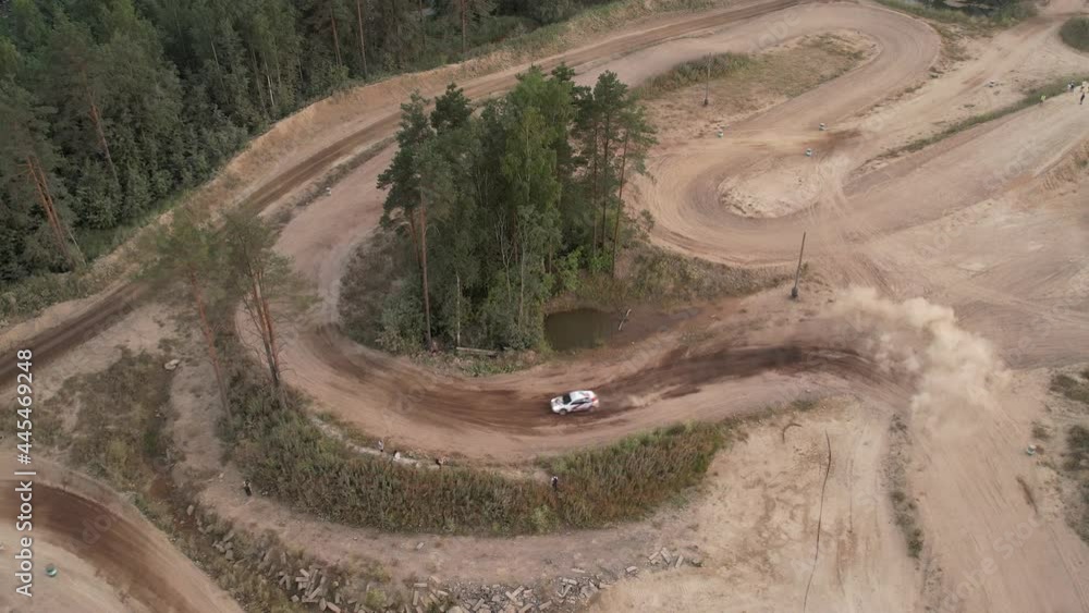 Aerial footage of a car race car driving into a drift on a dusty road ...
