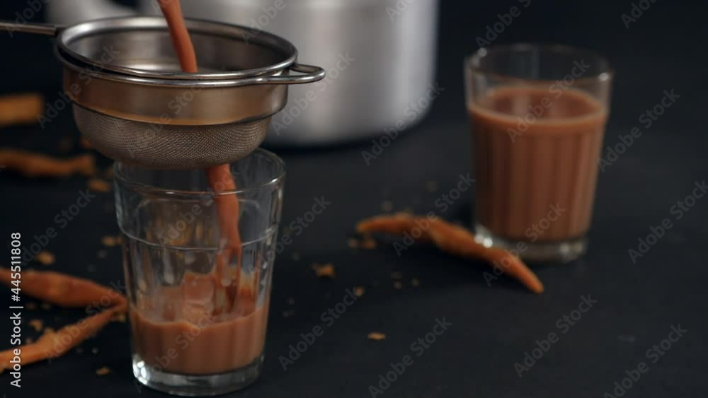 Hands holding a sieve to strain the tea pouring it into a transparent ...