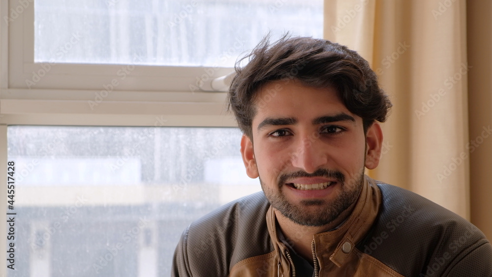 Handsome smiling Indian man looking at the camera against a wall with ...