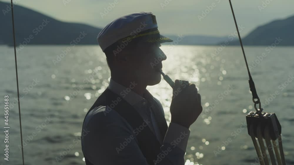 Sailor enjoying evening on sea with smoking tobacco pipe. Glittering ...