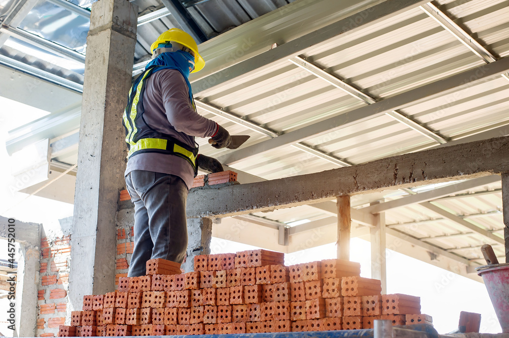 Builder carefully puts red brick on the masonry. Quick work bricklayer ...