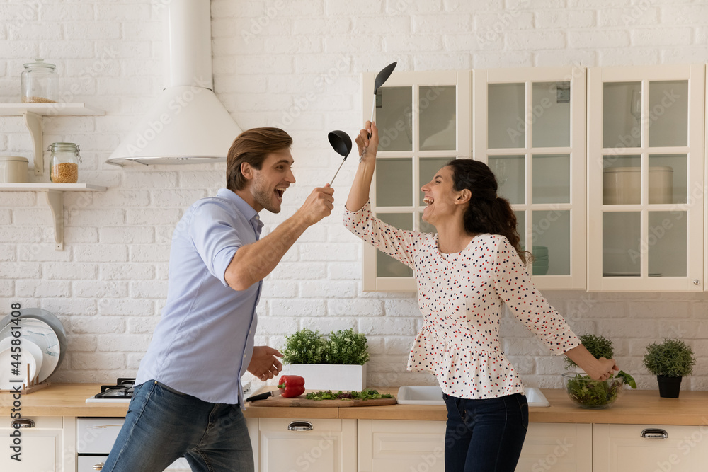 Food feud. Laughing spouses having fun at kitchen struggling in crazy ...