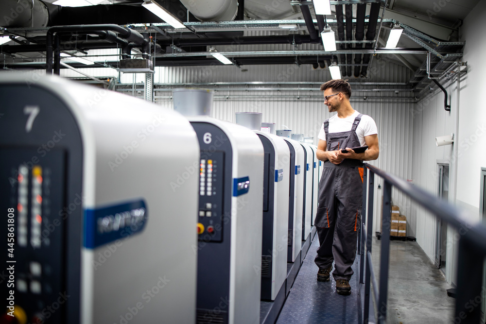 Printing house interior with modern offset print machine and operator ...