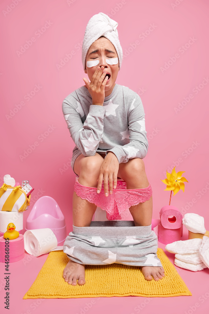 Upset Asian woman suffers diarrhea has sleepy look cries and poses on ...