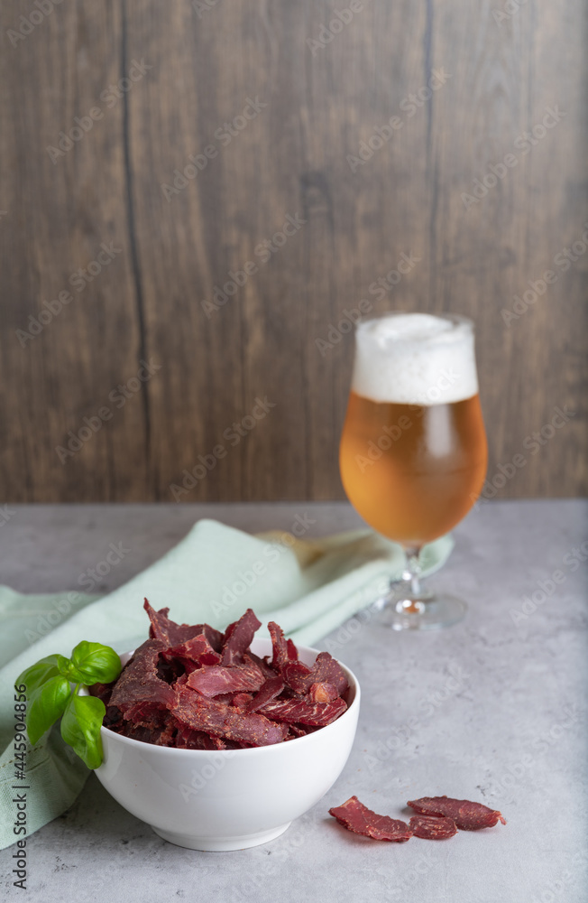 Jerky Beef, Jerky in white bowls with fresh basil on a concrete-wood ...