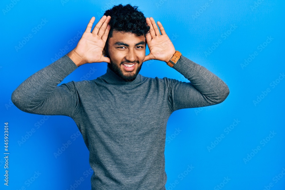 Arab man with beard wearing turtleneck sweater smiling cheerful playing ...