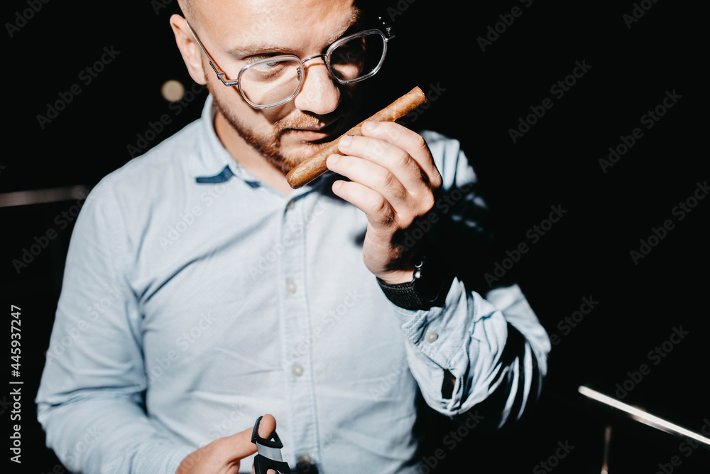 stylish man with a cigar on a dark background. Cigar clubs concept ...