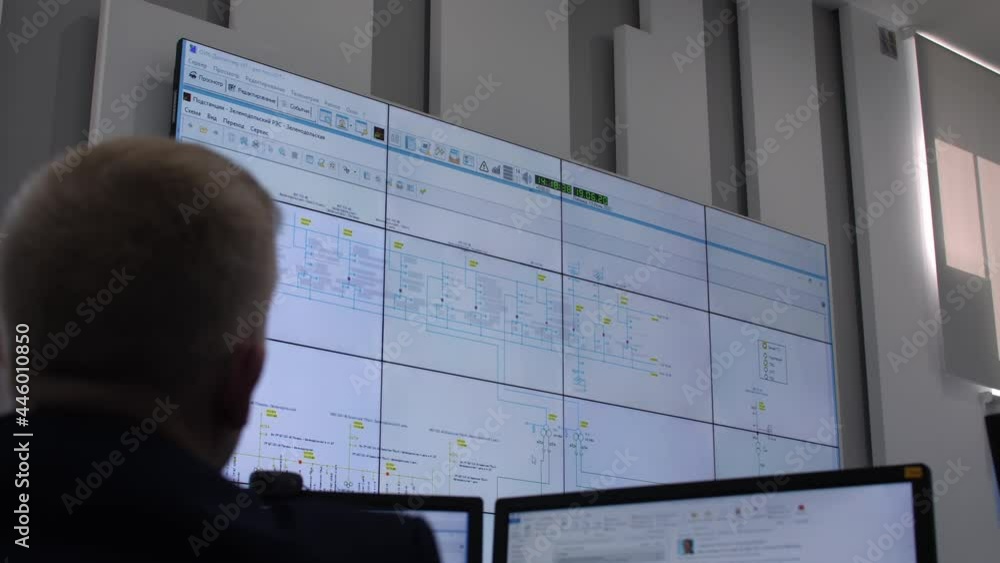 Engineer looks at monitor with equipment connection scheme in spacious ...