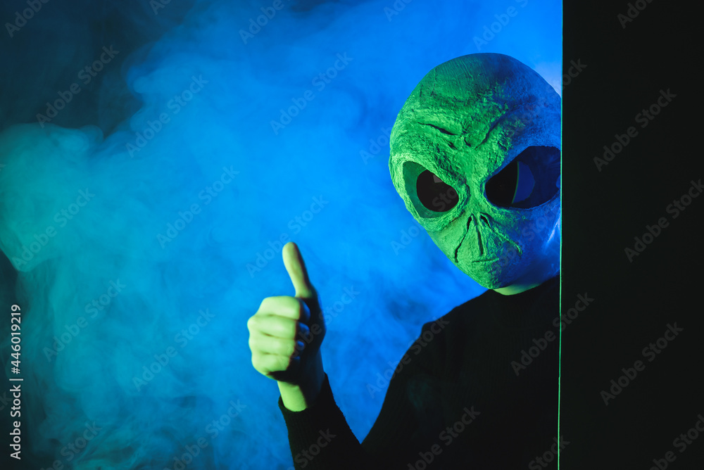 Alien looks out from a wall and shows a thumbs up gesture. Stock Photo ...