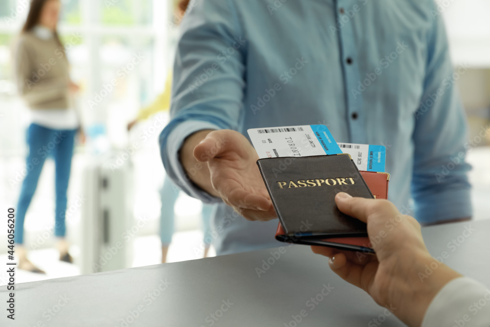 Agent giving passports and tickets to man at check-in desk in airport ...