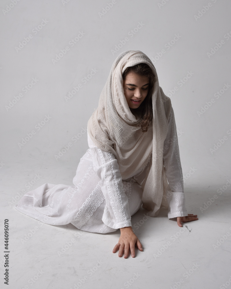Full length portrait of young woman wearing classical white gown and a ...