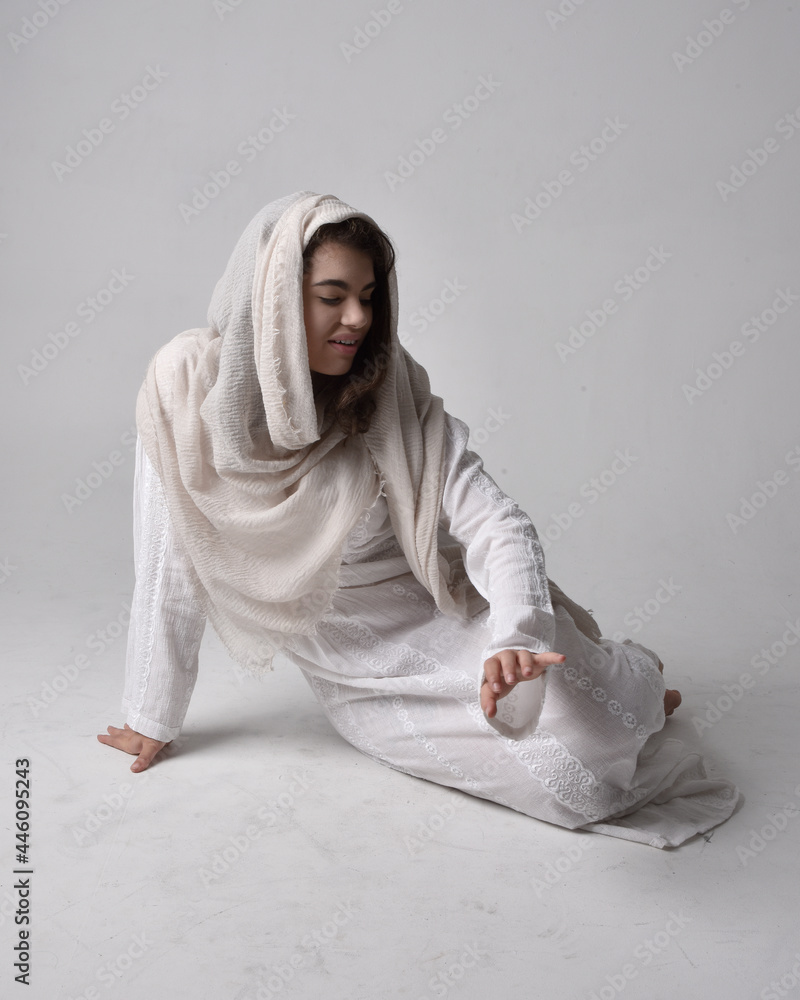 Full length portrait of young woman wearing classical white gown and a ...