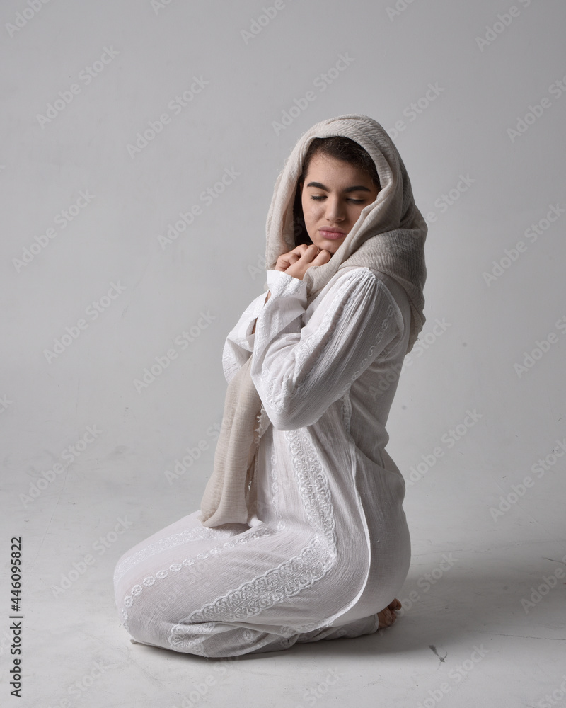 Full length portrait of young woman wearing classical white gown and a ...