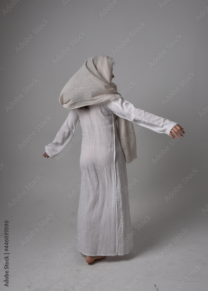 Full length portrait of young woman wearing classical white gown and a ...