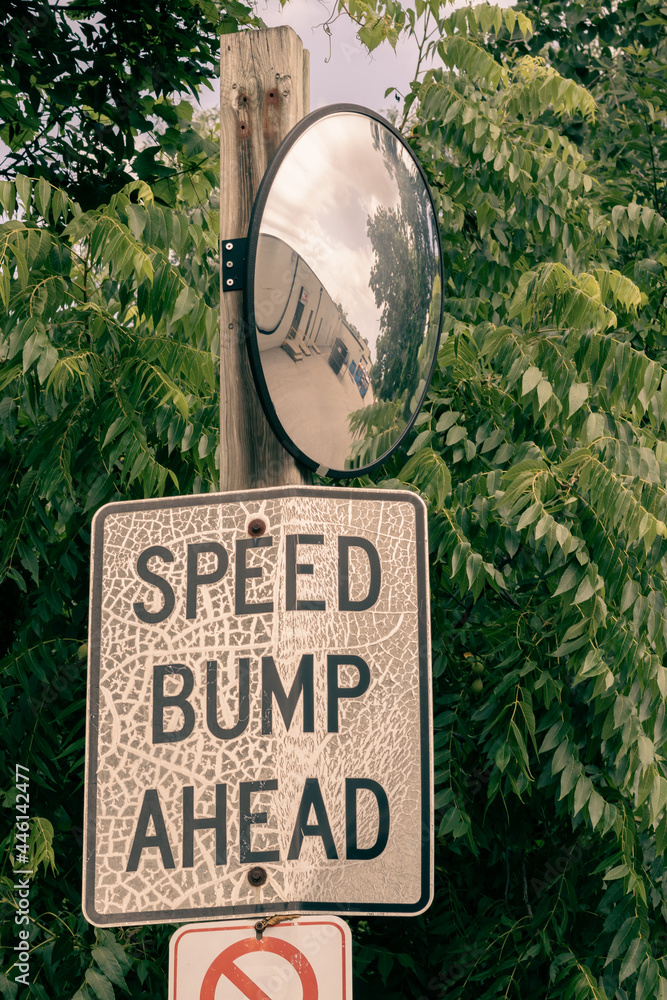 Vertical of speed bump ahead sign below convex safety mirror Stock ...