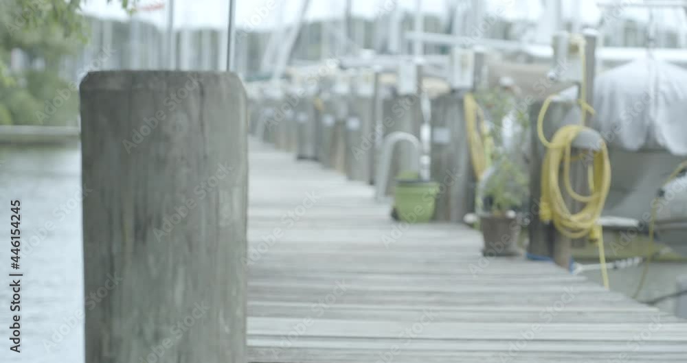 Rack focus from tall thick gray wooden pier pylon to pedestrian walkway ...