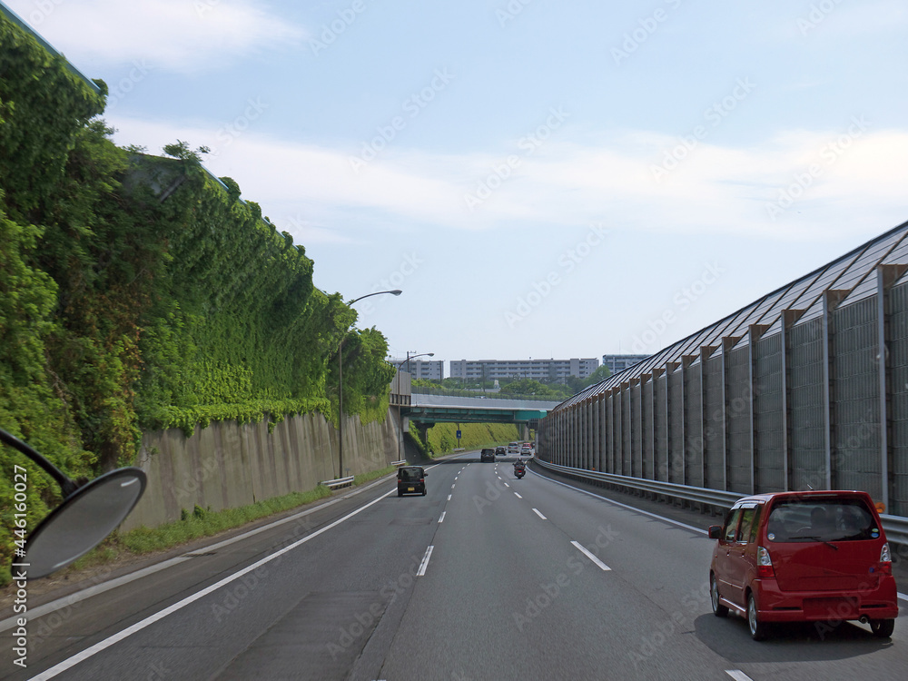 Entering Tokyo by highway with tall green Overgrown noise barriers with ...