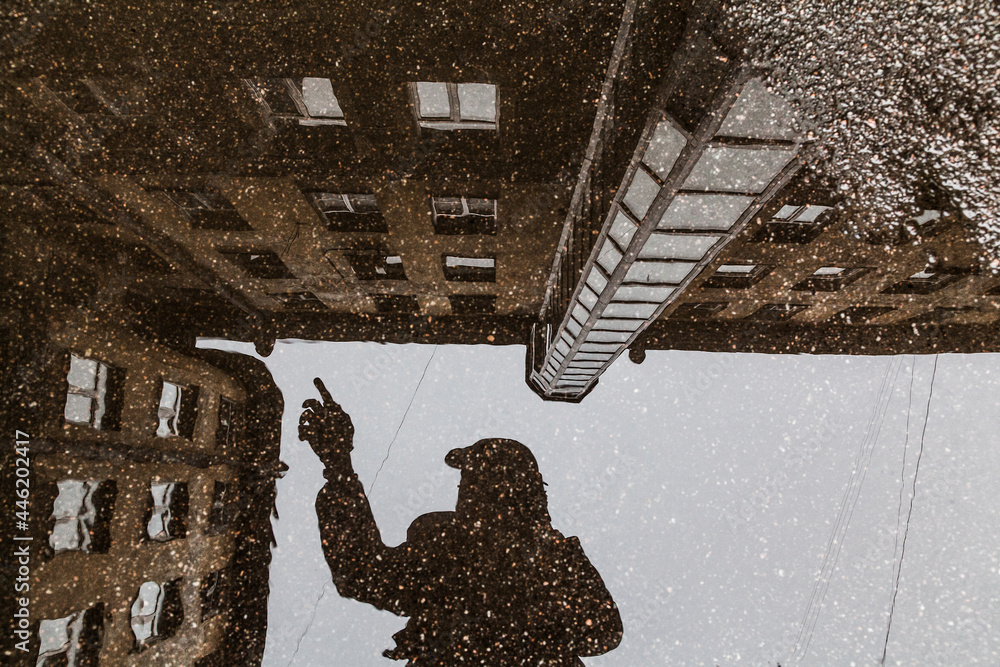 Black silhiuette of man reflected in puddle inside vintage courtyard ...