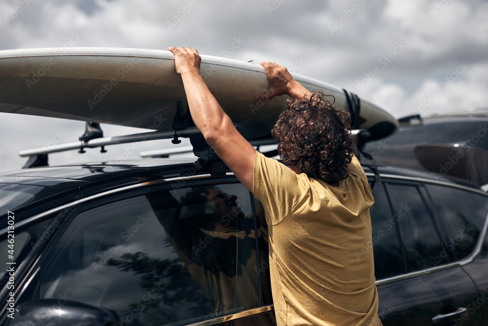 Windsurfer and camper packing and unpacking from a car's roof rack in ...