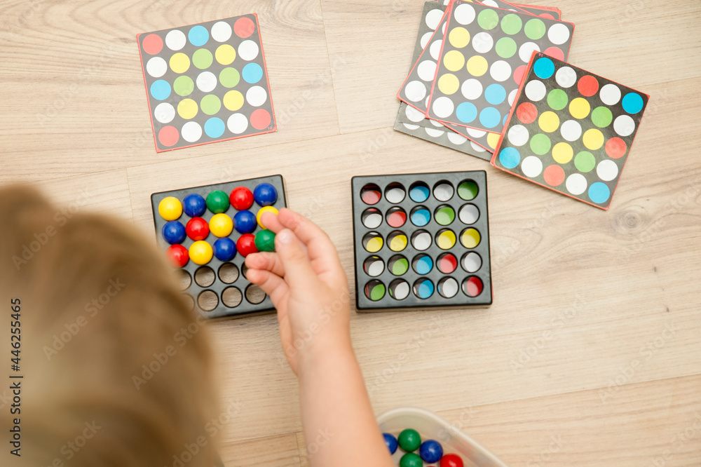 Childs hand on colorful wooden marbles. Color sequence logic game. A ...