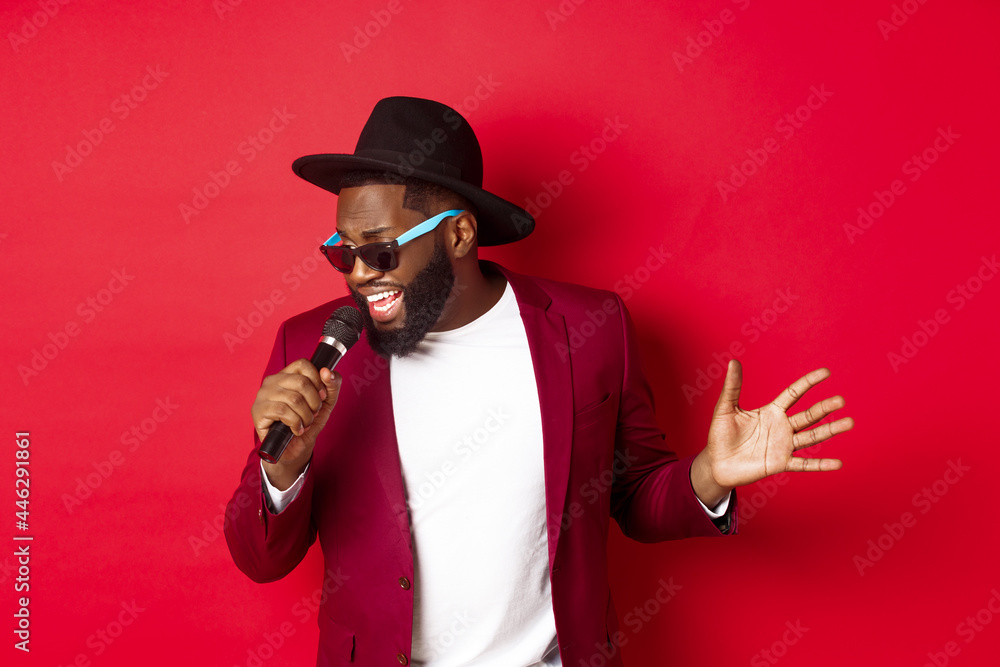 Passionate black male singer performing against red background, singing ...