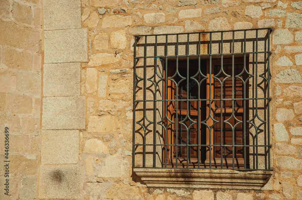 Wooden window with wrought iron grid on the stone facade of gothic ...