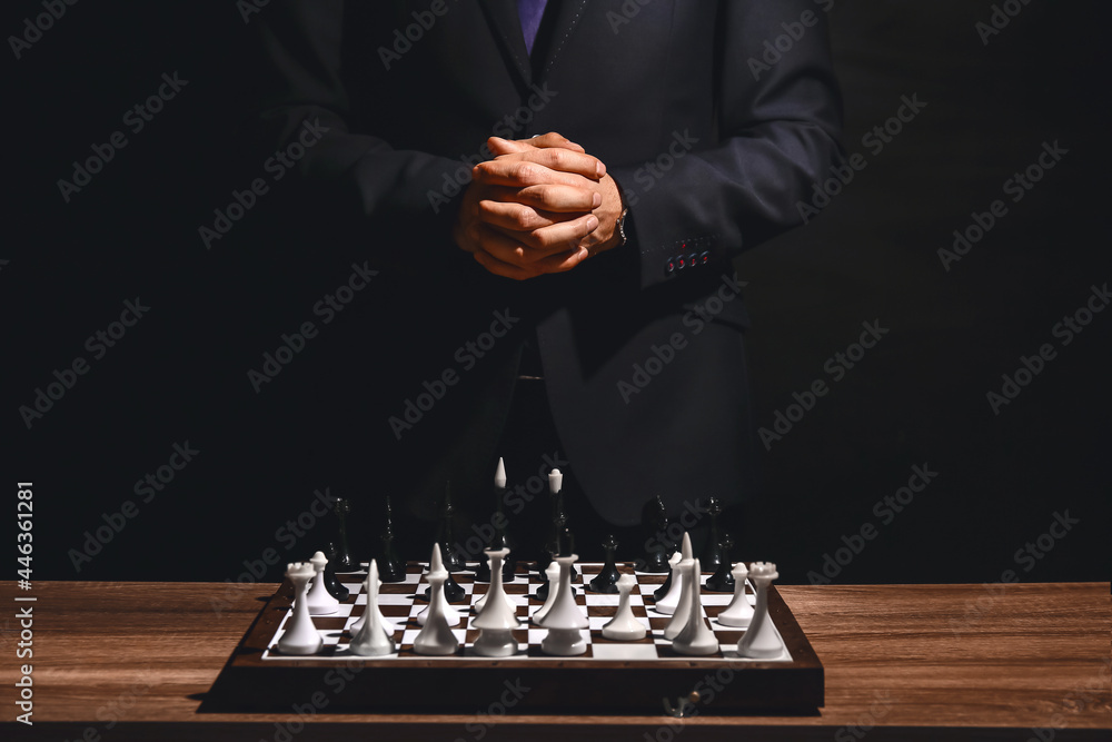 Man playing chess at table on dark background Stock Photo | Adobe Stock