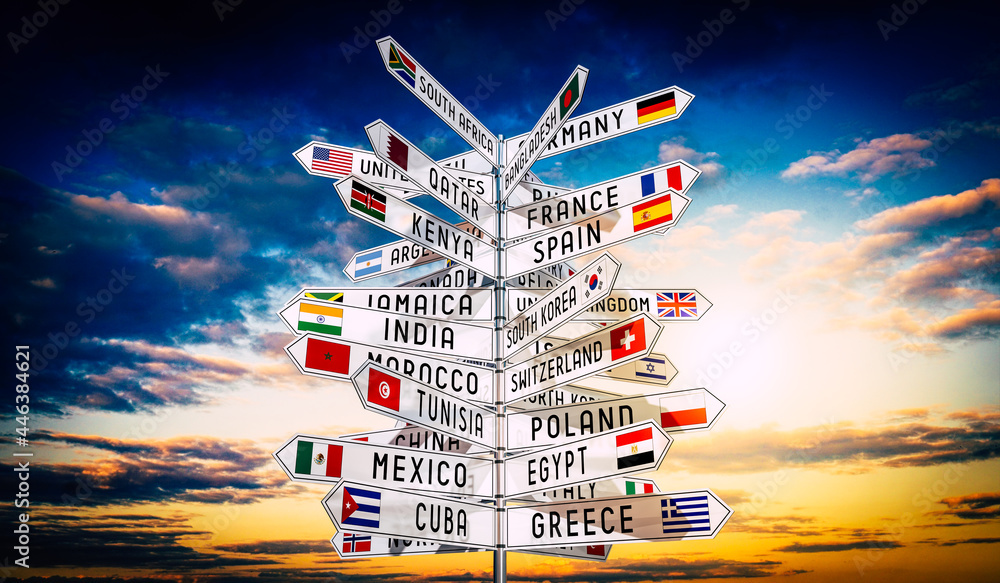 Signpost with national flags of different countries, sky in background ...