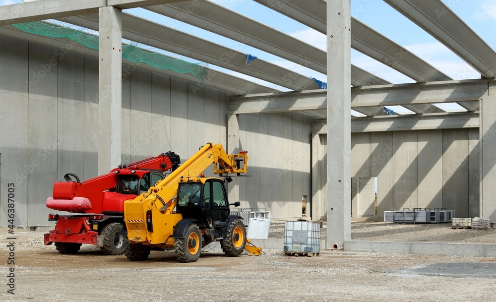 Back of two telescopic handlers inside a concrete block building under ...