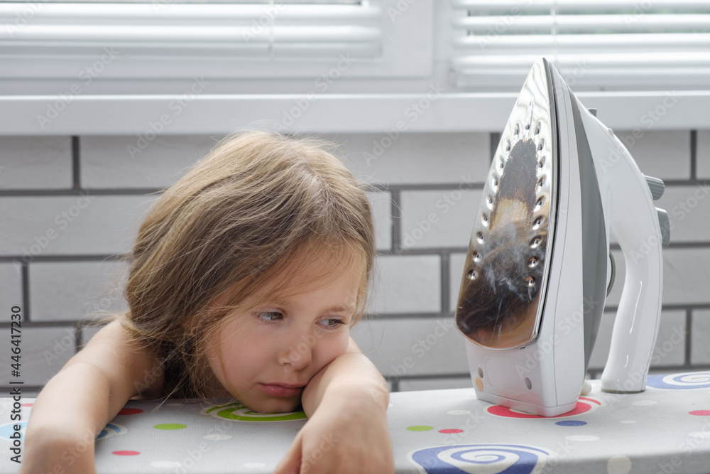 child daughter ironing clothes iron in laundry at home. the child ...