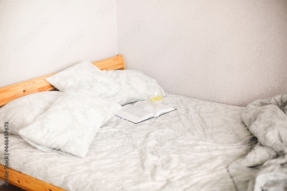 Side view of morning bed after awakening with open book and glass of ...
