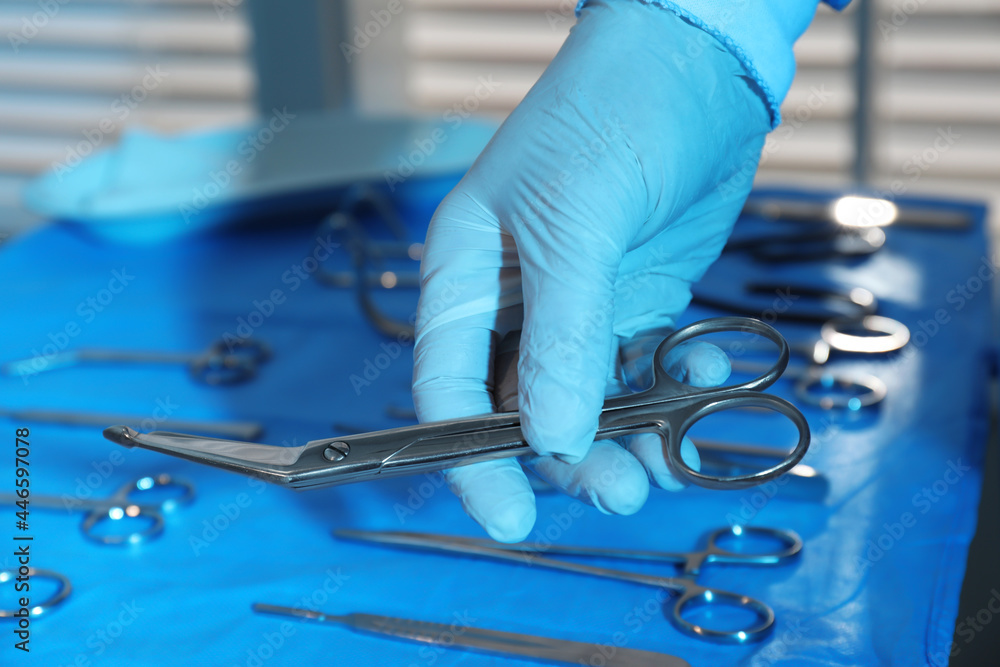 Doctor taking Pott's scissors from table with different surgical ...