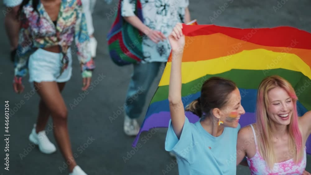 A group of lgbt people are walking on the street holding and waving ...