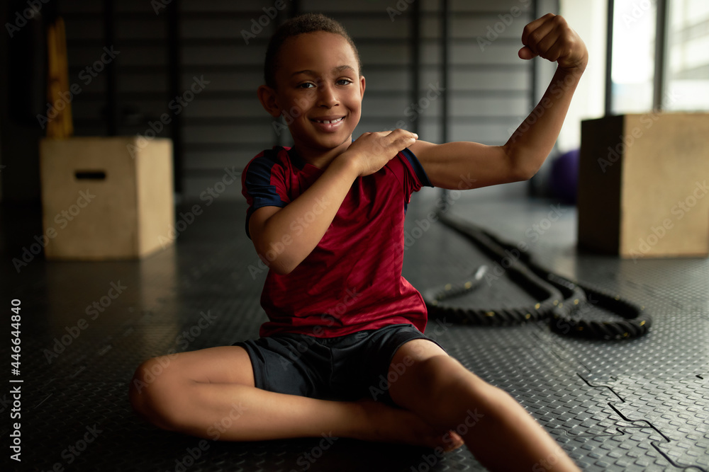 Smiling latino american child showing how big his muscles sitting on ...