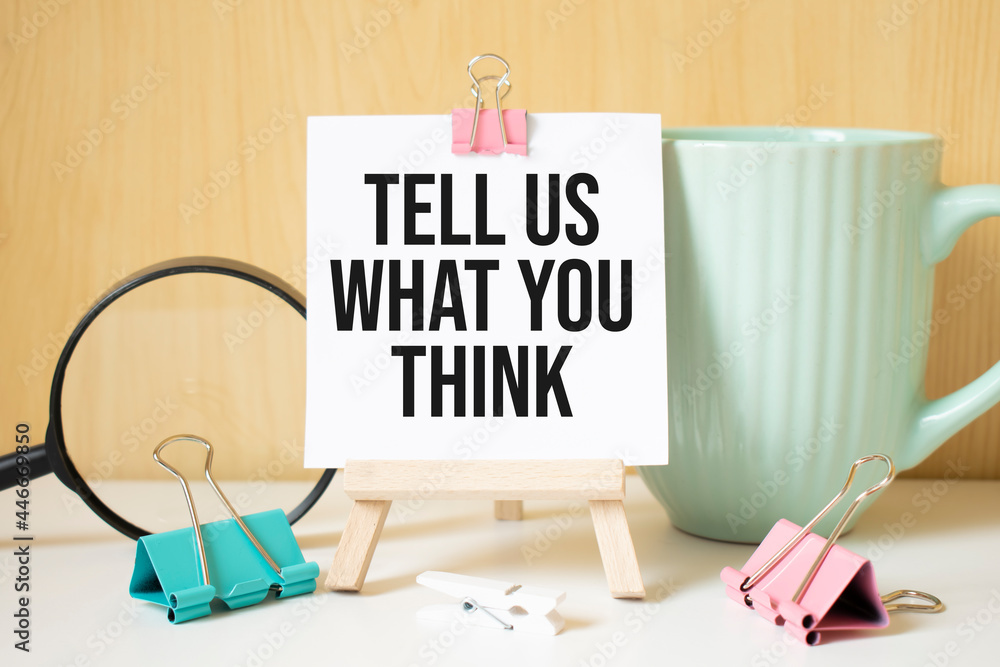 Tell us what you think text written on black notebook with magnifying ...