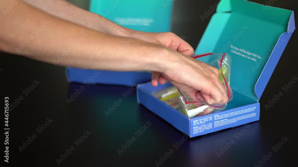4K clip of woman's hands unpacking contents of a COVID19 home test kit ...
