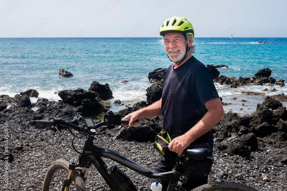 Sporty senior man standing with his e bike close to the sea. Active ...