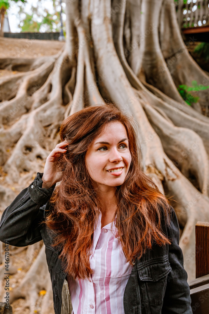 Beautiful woman walks through a rainforest with trees with huge roots ...