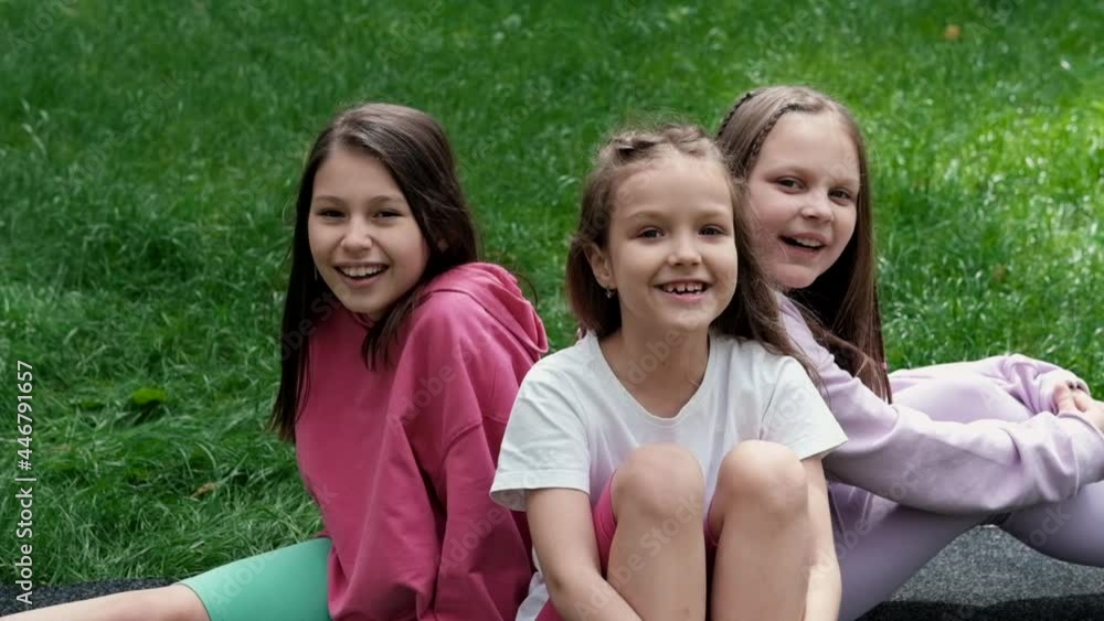 three beautiful happy tween teenagers girls in colorful clothes sitting ...