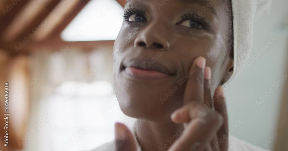 Portrait of african american attractive woman applying face cream in ...