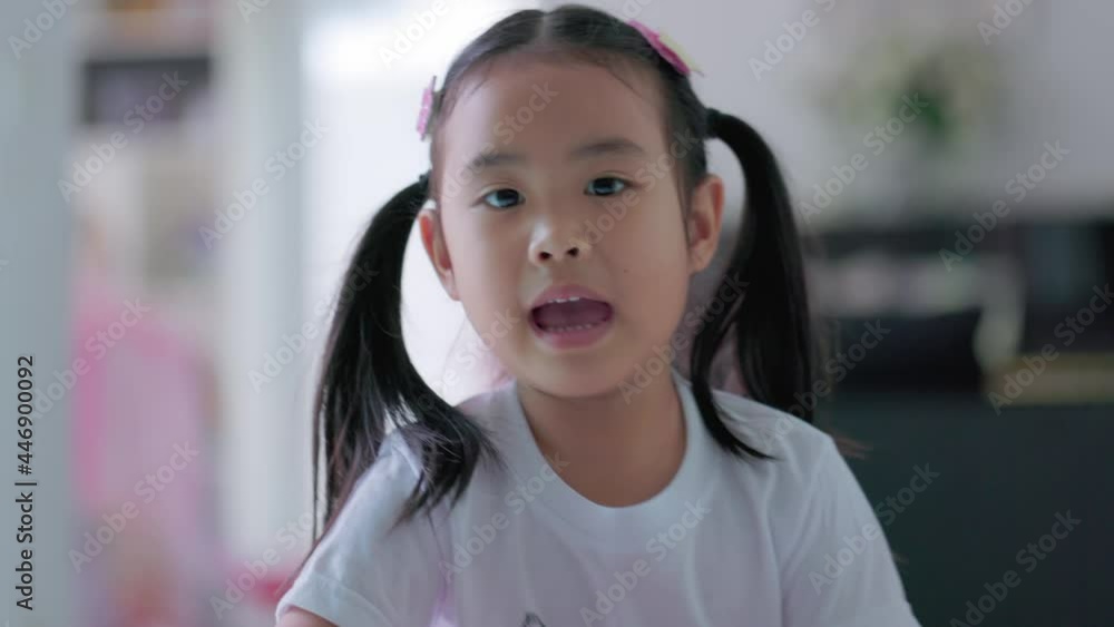 Cute Asian girl waving hello looking at the camera. Daughter is playing ...