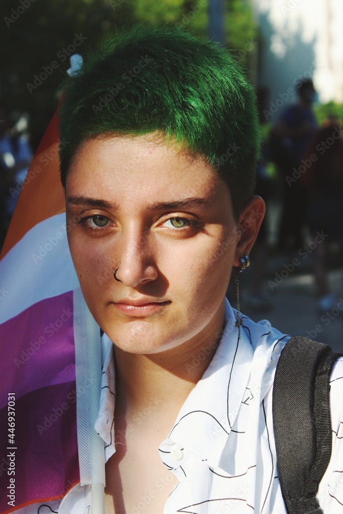 portrait of queer young woman with green hairstyle & eyes holding ...